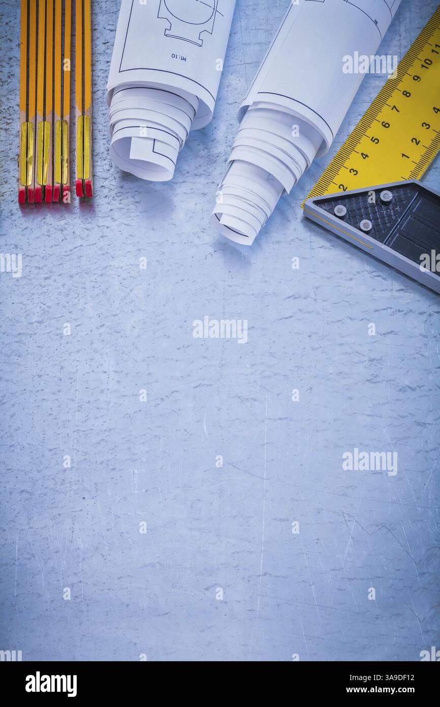 Wooden meter rolls of blueprints square ruler on metallic background ...