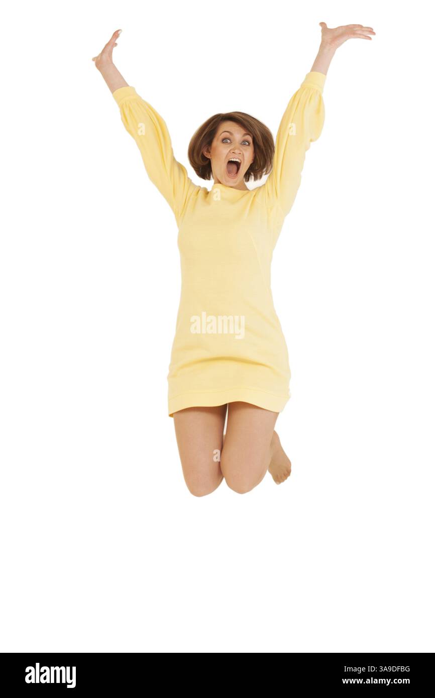 Beautiful adult woman jumping with hands up against of white background ...