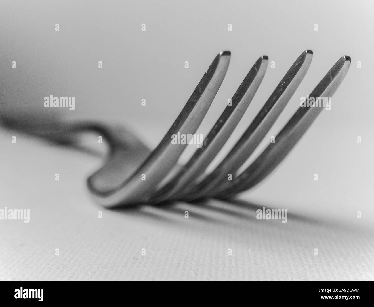 Fork is shown in a black and white photo. The fork is bent at the top ...