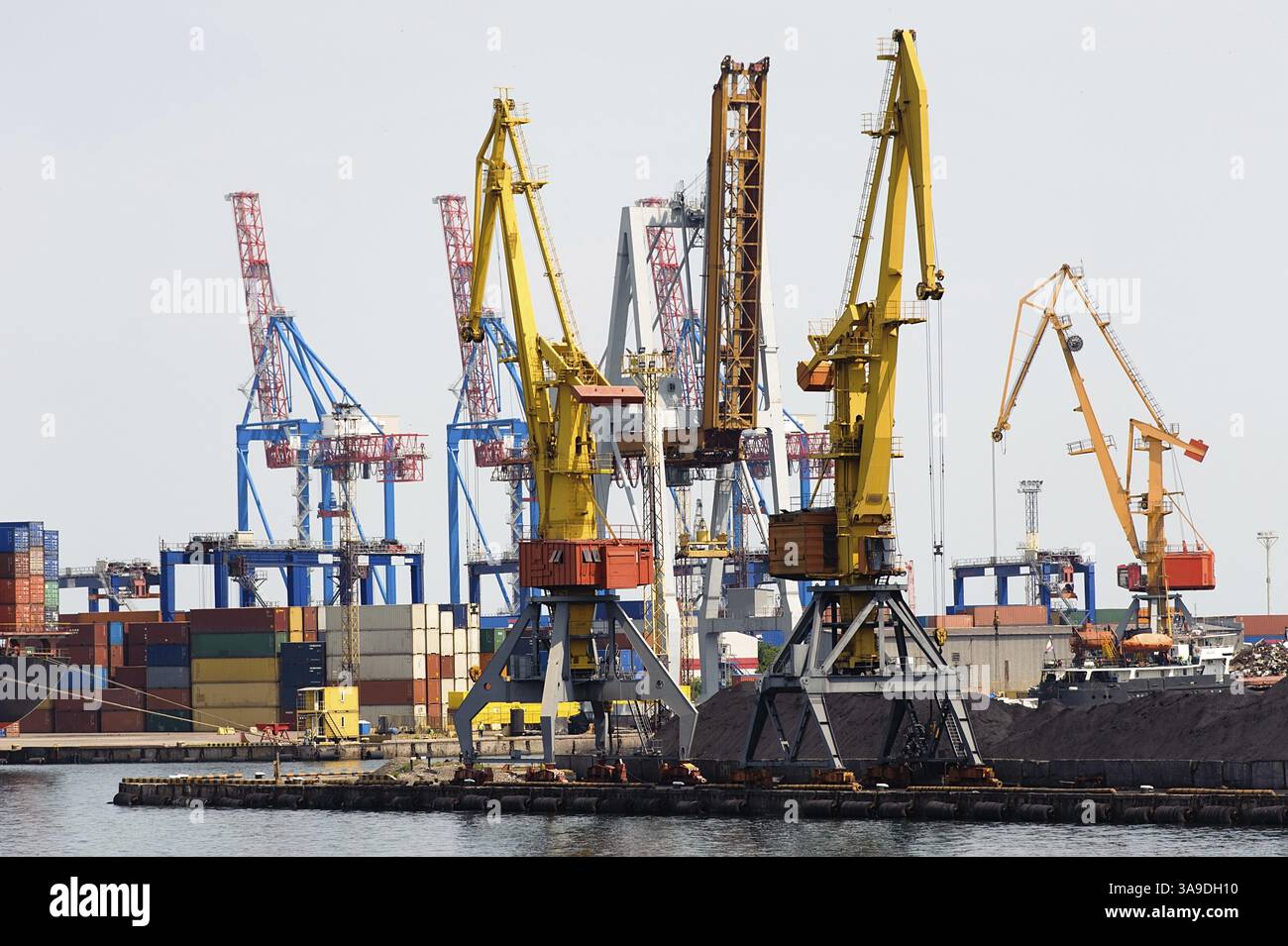 Industrial cranes and cargo on a quay in a docks waiting to be loaded ...