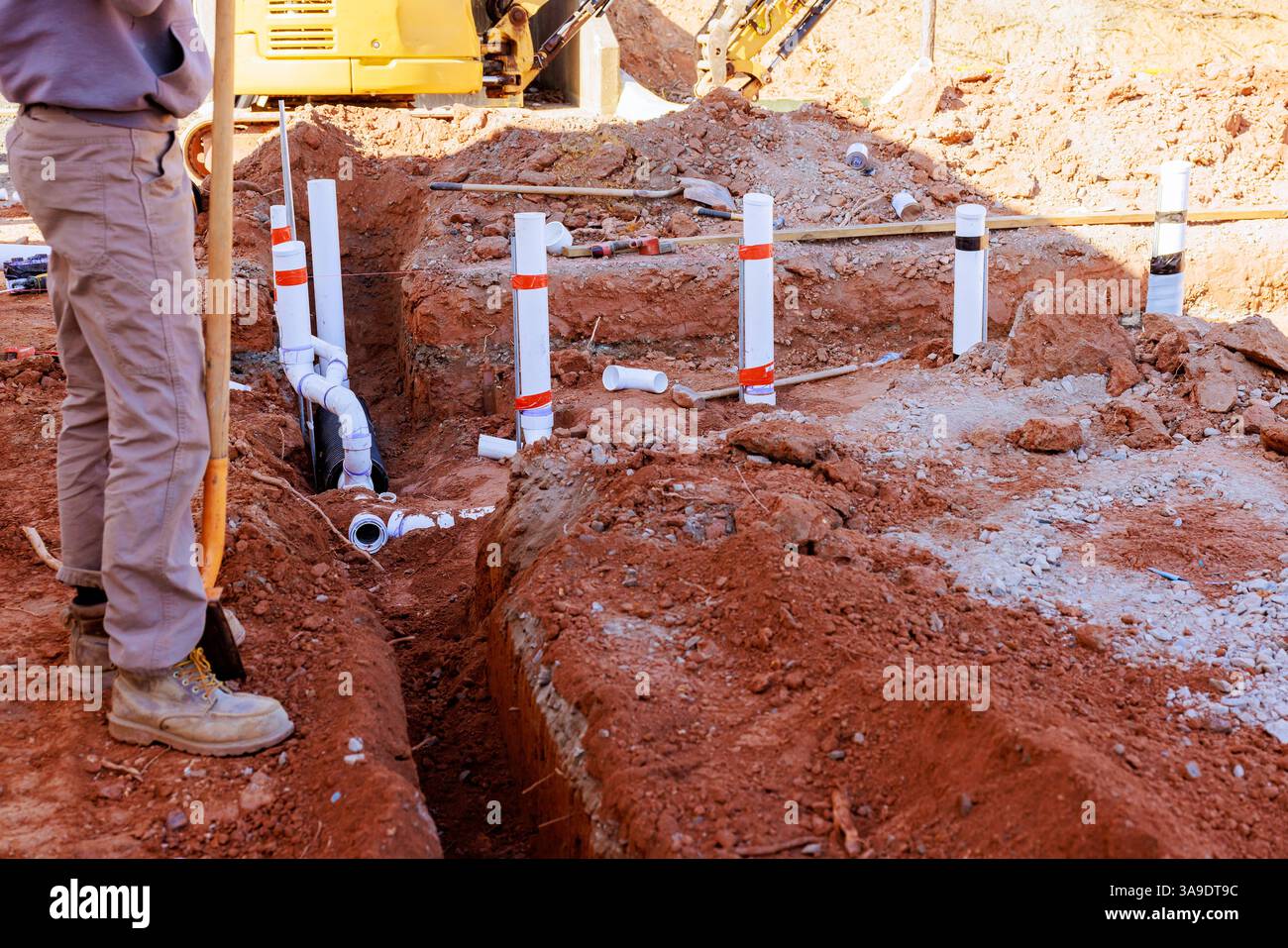 Workers are digging trenches laying out plumbing pipes at construction ...