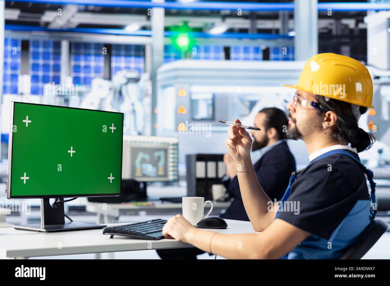 Technician uses green screen PC to monitor solar panel manufacturing plant assembly lines ...