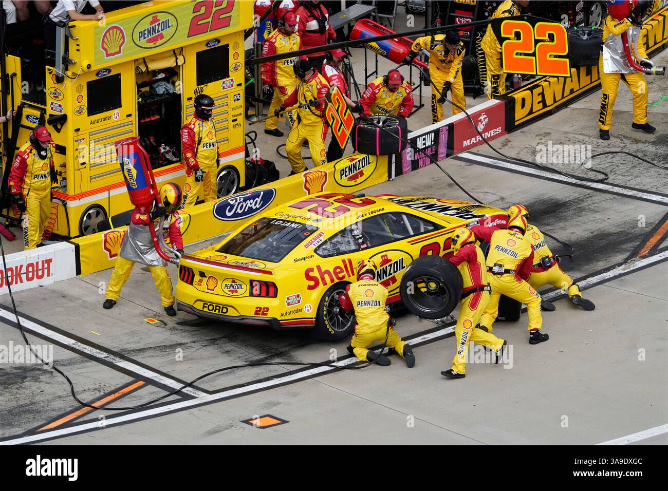 Crew members perform a pit stop on driver Joey Logano's car during a ...