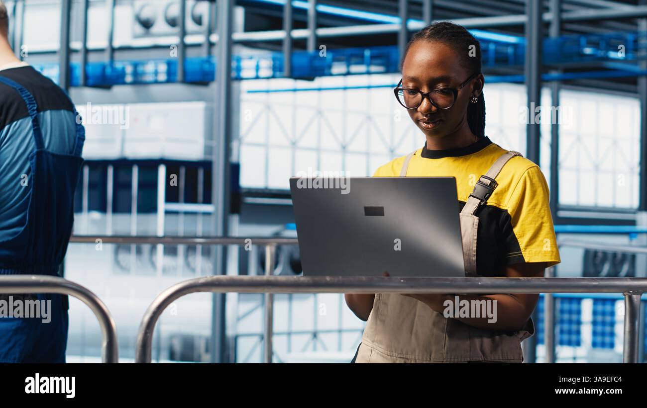 Smart factory engineer oversees operation of robotic arms and conveyor ...