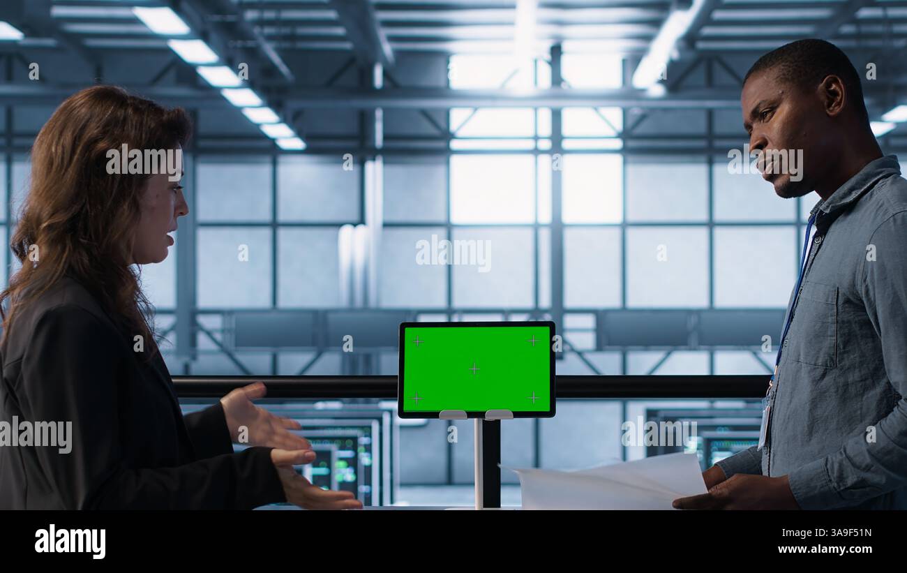 Engineers overseeing server room with mockup device, reading hardware ...