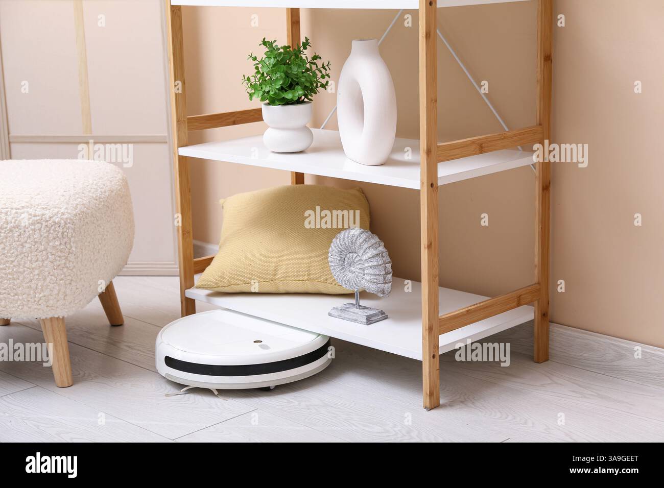Modern robot vacuum cleaner under shelving unit at home Stock Photo - Alamy