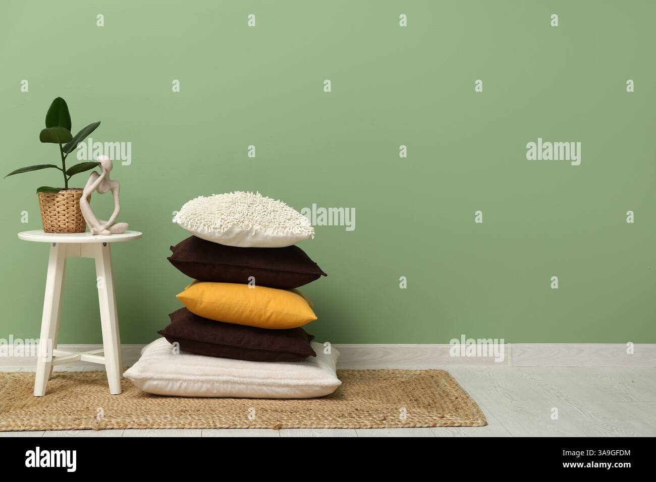 Stack of cushions on carpet and plant with human figure on coffee table ...
