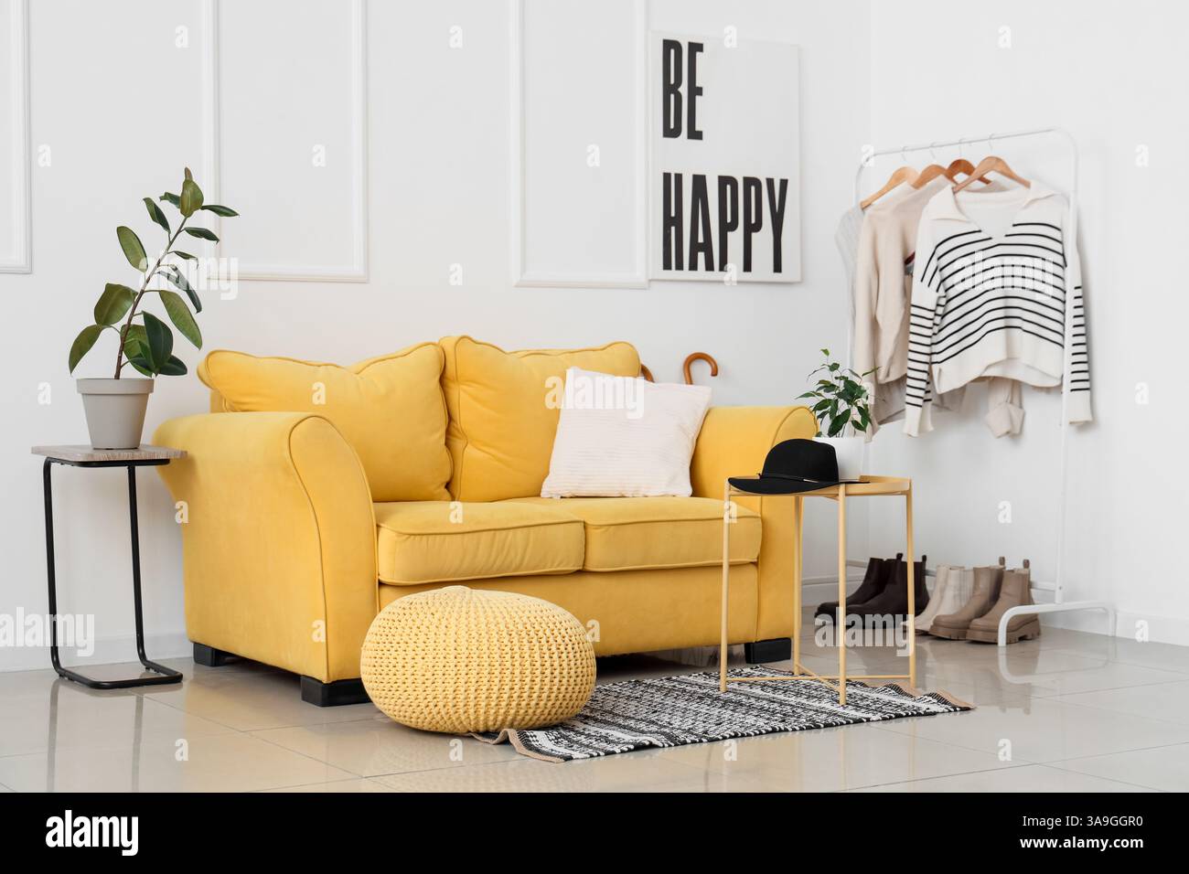 Cozy sofa, rack with clothes and coffee table in interior of hallway ...