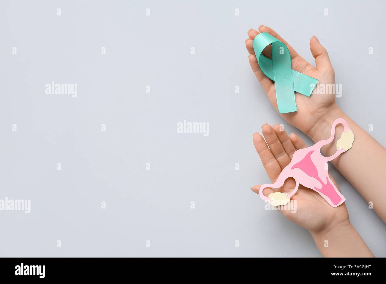 Female hands with turquoise ribbon and paper uterus on white background ...