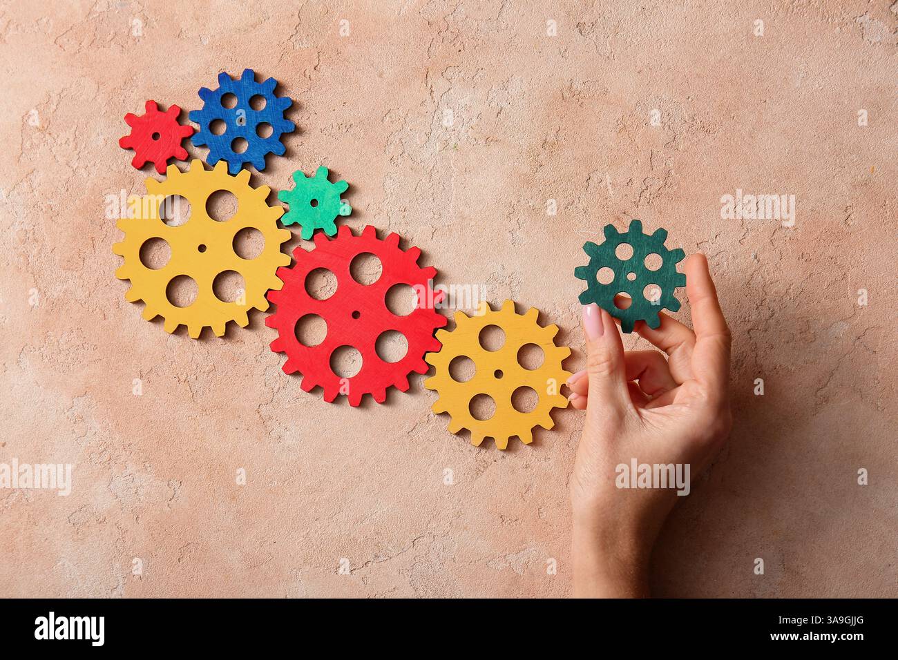 Hand with wooden gears on grunge background Stock Photo - Alamy