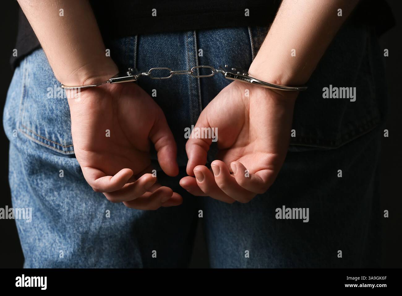 Young man in handcuffs on black background, back view Stock Photo - Alamy