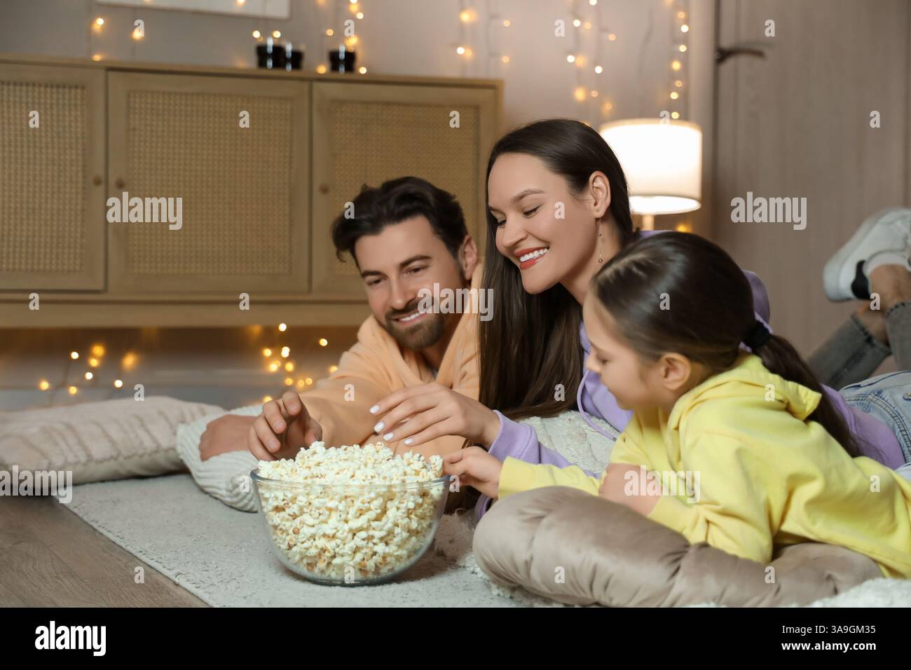 Family eating popcorn while watching movie at home Stock Photo - Alamy