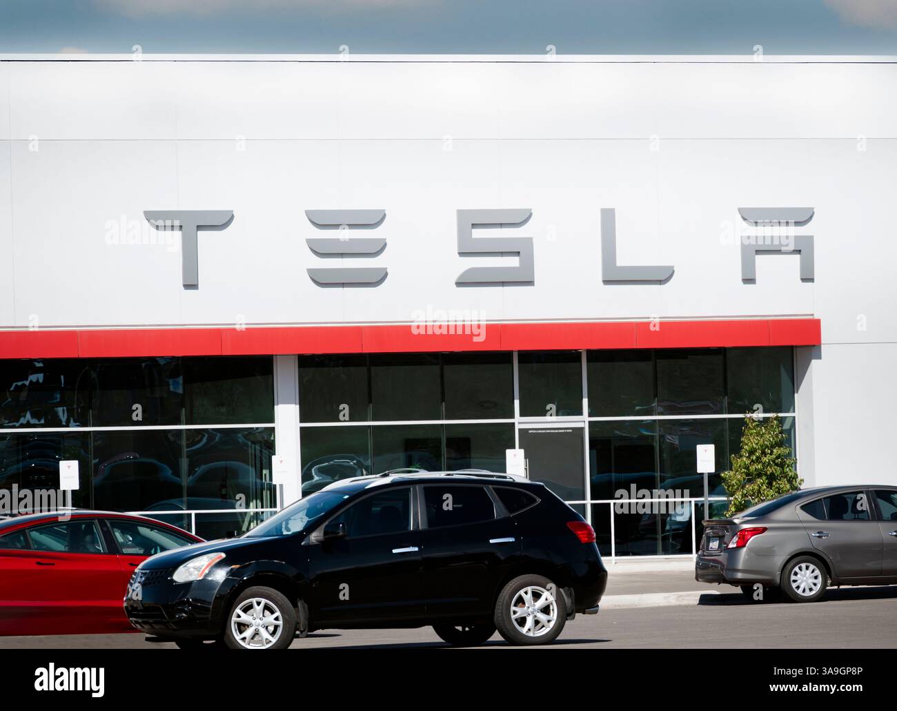 Tesla Dealership with logo on modern building and Tesla cars parked in ...