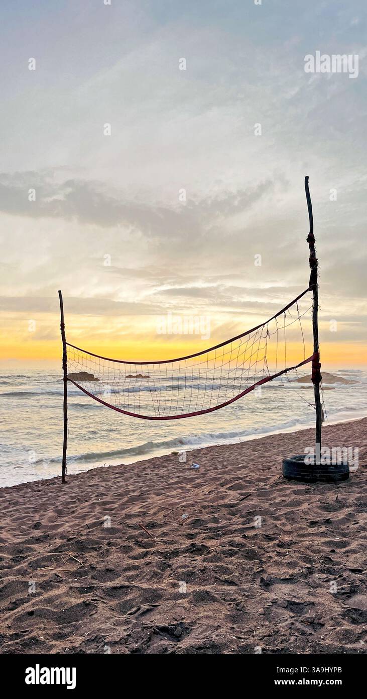 Old and uneven volleyball net on the beach in Peru during a sunset ...