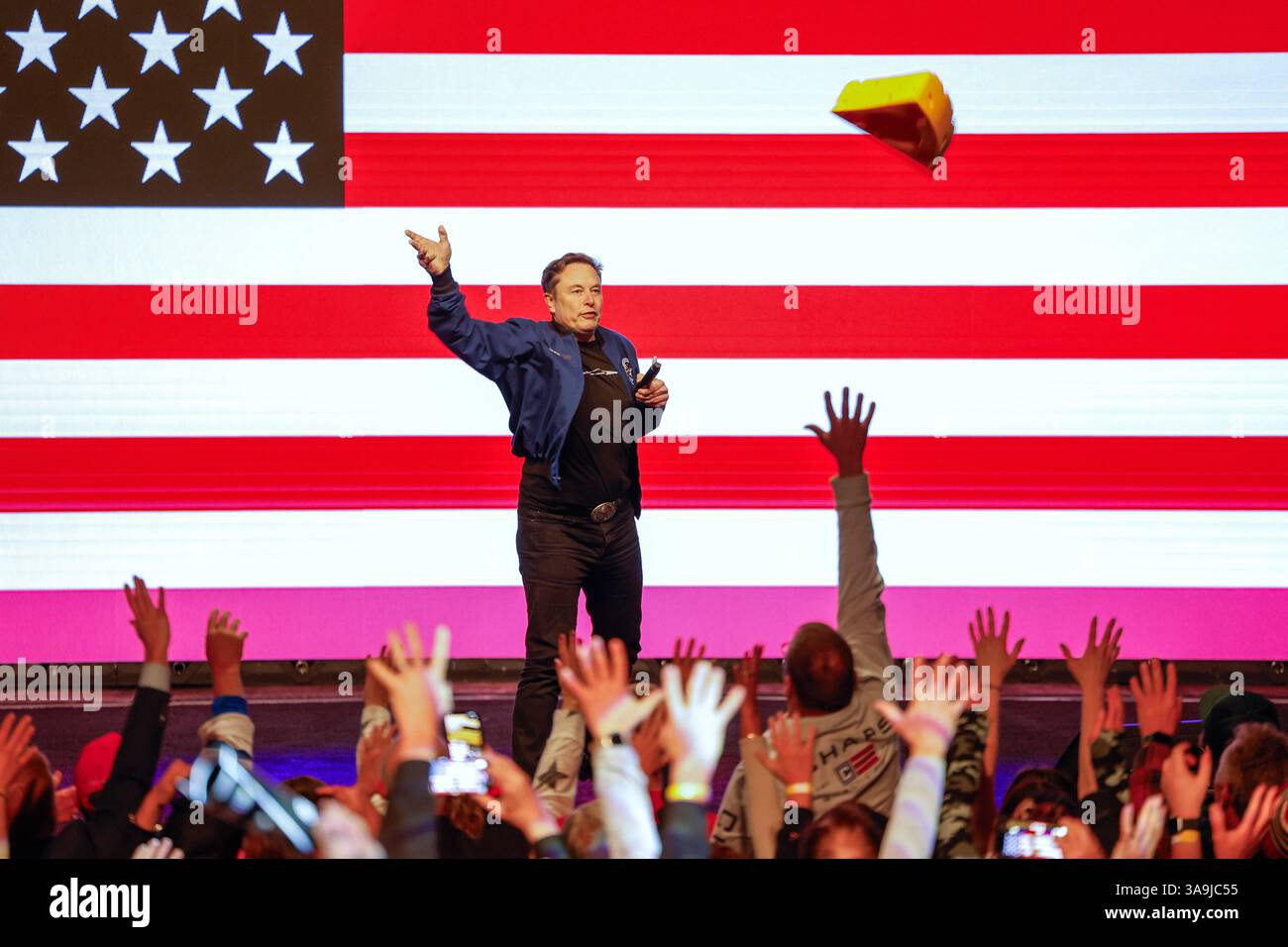 Elon Musk tosses a cheesehead during a town hall Sunday, March 30, 2025 ...