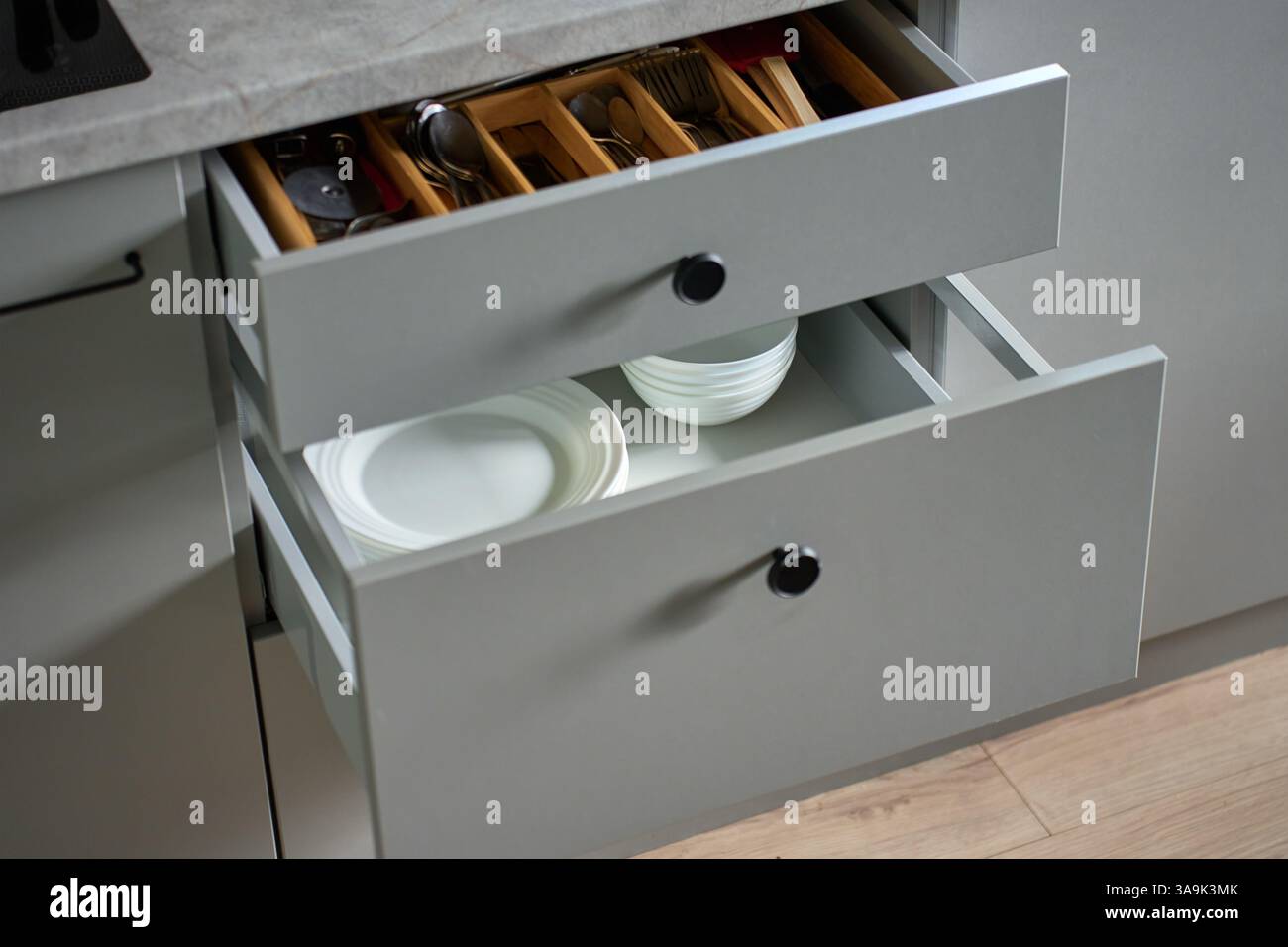 Modern kitchen with dishes and cutlery in open drawers. Contemporary ...