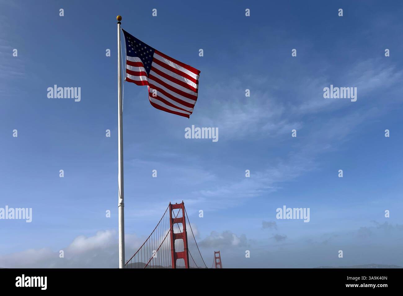 A vibrant American flag flutters atop a flagpole with the iconic Golden ...