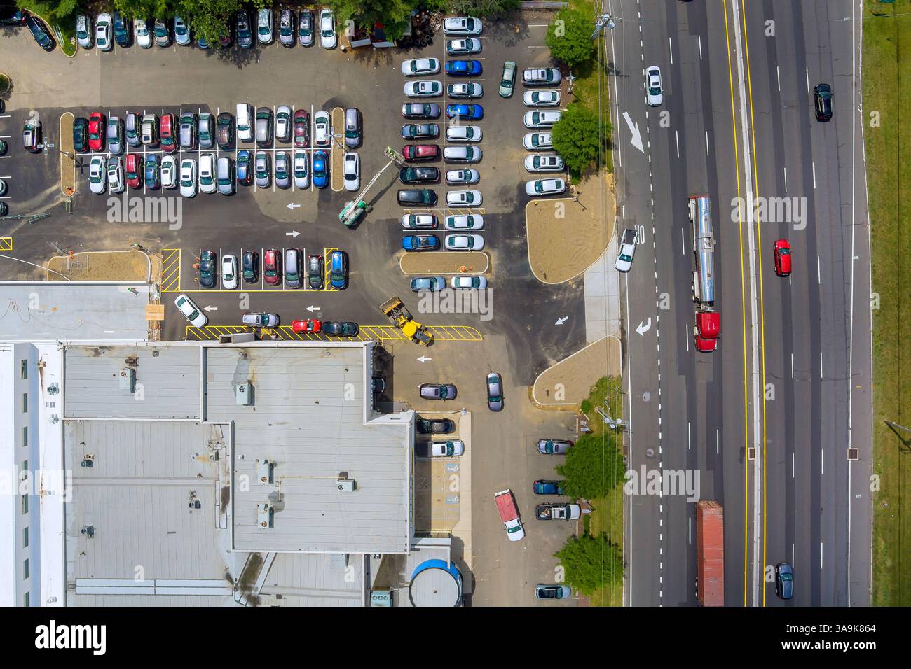 Aerial view of busy parking lot filled with cars alongside main roadway ...