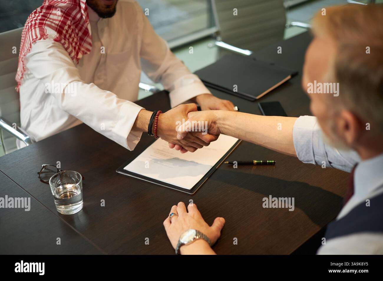 High angle view of two ethnically diverse businessmen doing handshake ...