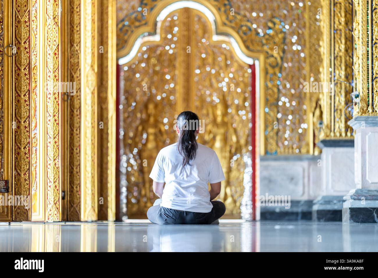Asian Man meditates on the ground with reflection in the sunlight ...