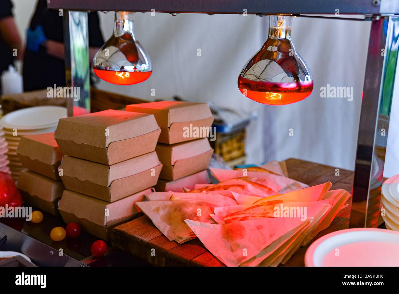 Freshly prepared hot meals under heat lamps with stacked takeout boxes ...