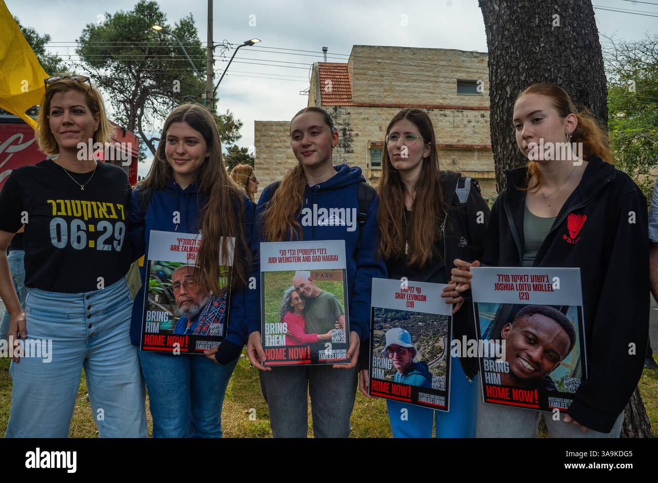 Haifa, Israel - March 27, 2025: Students and others stand outside of high school gate, part of ...