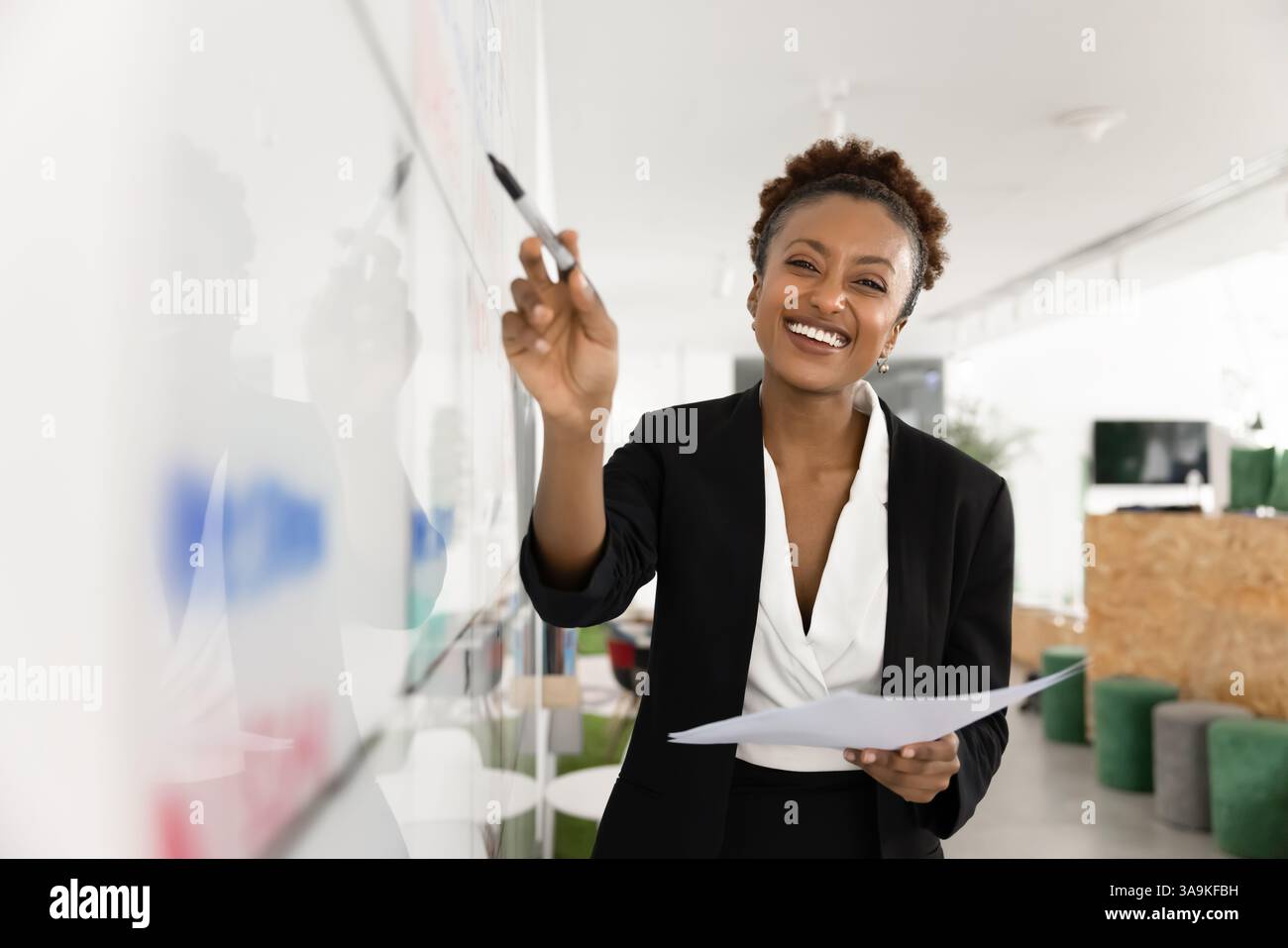 Cheerful positive young Black businesswoman writing on whiteboard Stock ...