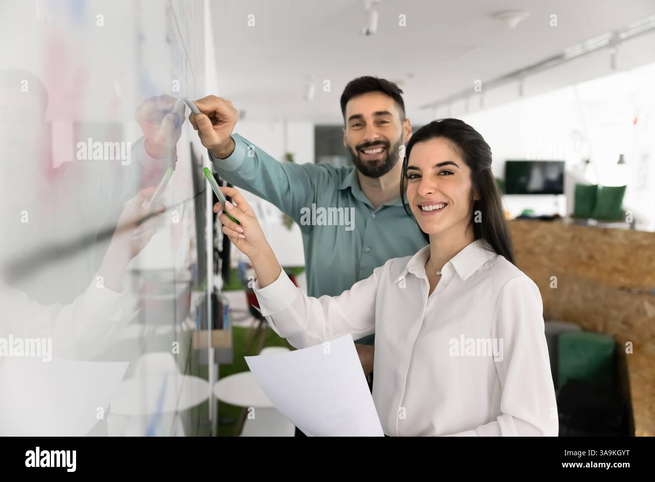 Happy business man and woman pointing pen at training whiteboard Stock ...