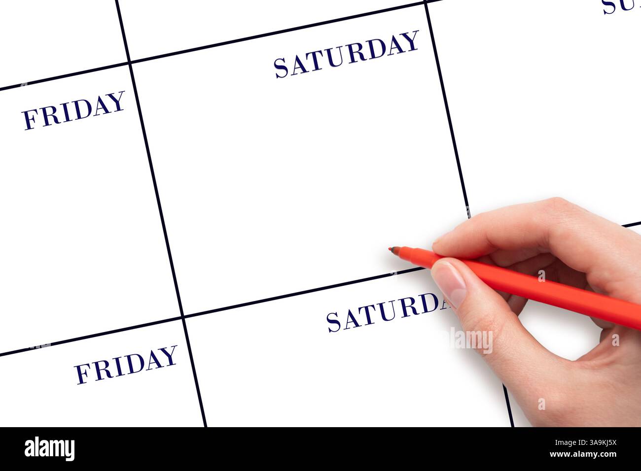 SATURDAY. Hand holding red pen writing in blank Saturday cell of a ...