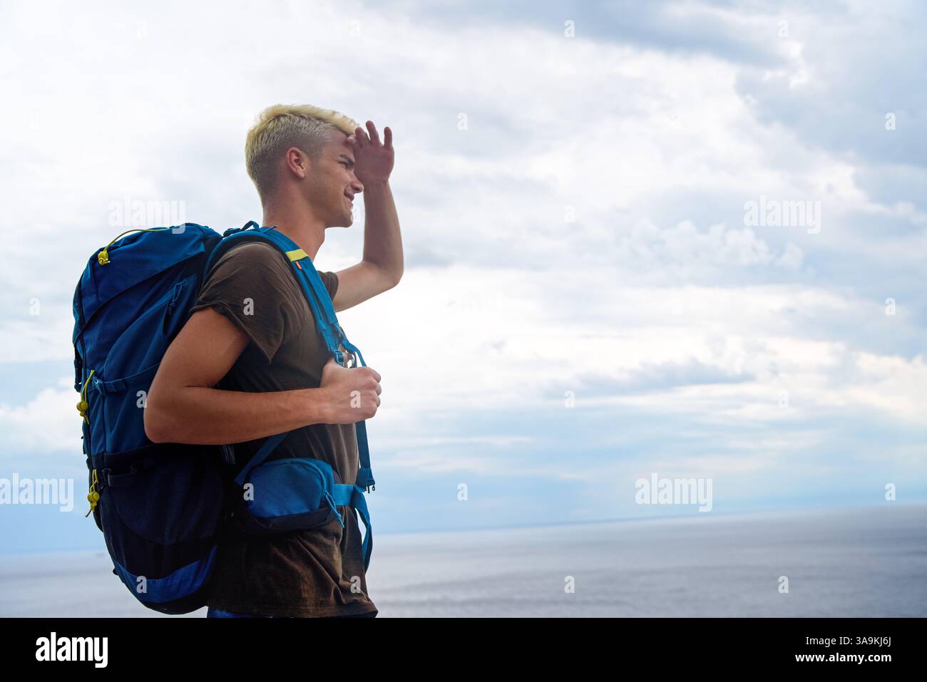 Young man traveler and explorer is hiking the hill. Overlooking sea ...