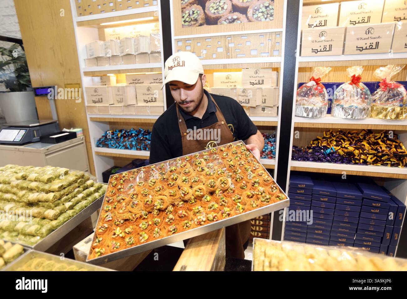 Baghdad, Iraq. 30th Mar, 2025. A man shows traditional sweets at a ...