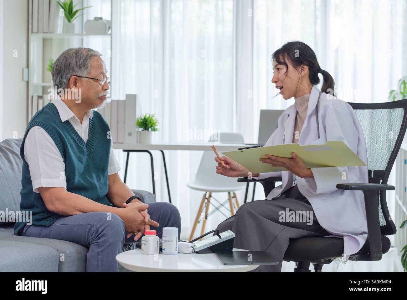 Doctor Reviewing Medical File While Interviewing Elderly Patient at ...