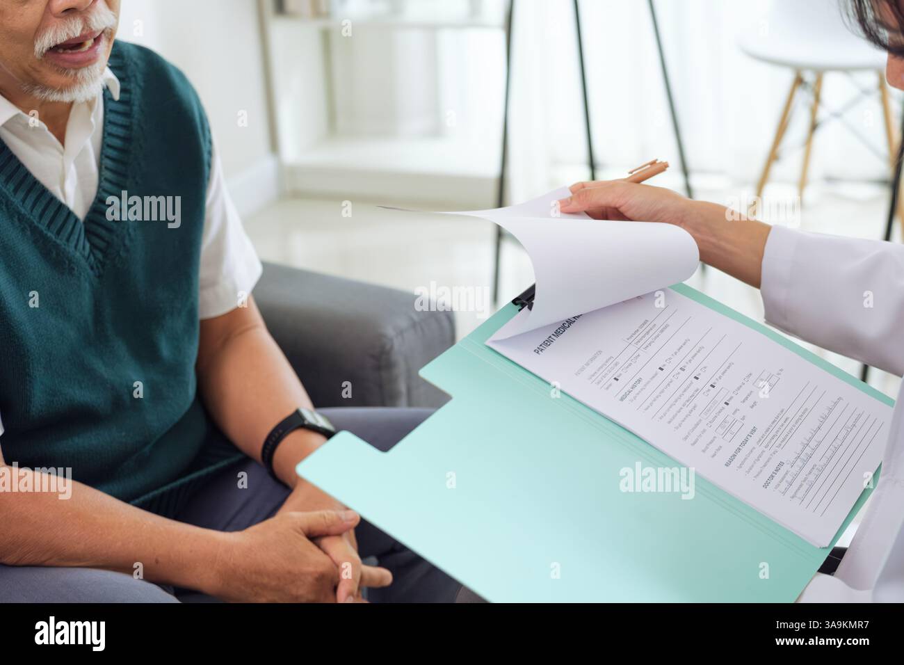 Doctor Reviewing Medical File While Interviewing Elderly Patient at ...