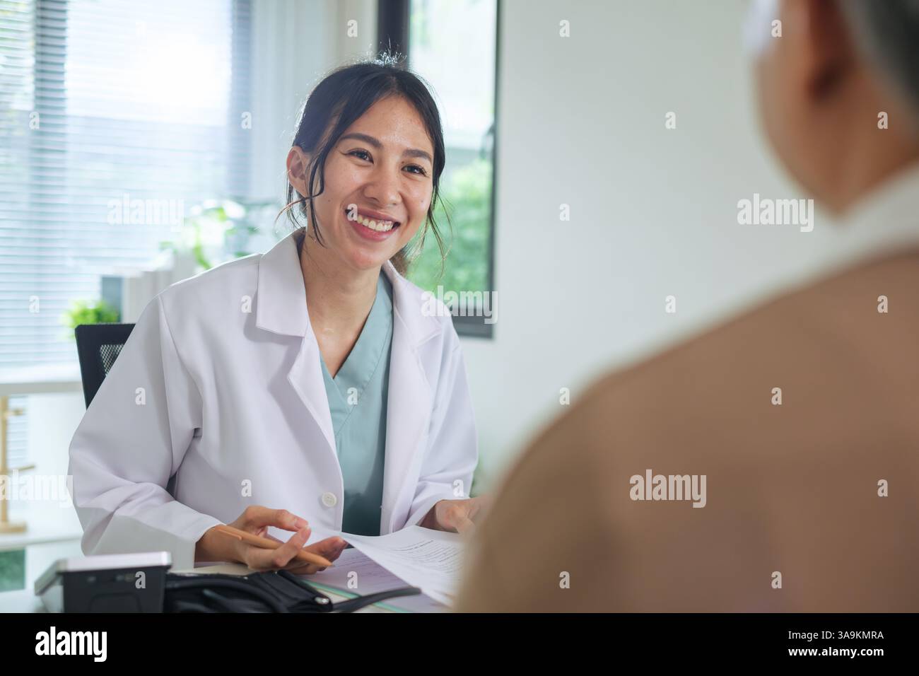 Doctor Reviewing Medical File While Interviewing Elderly Patient at ...