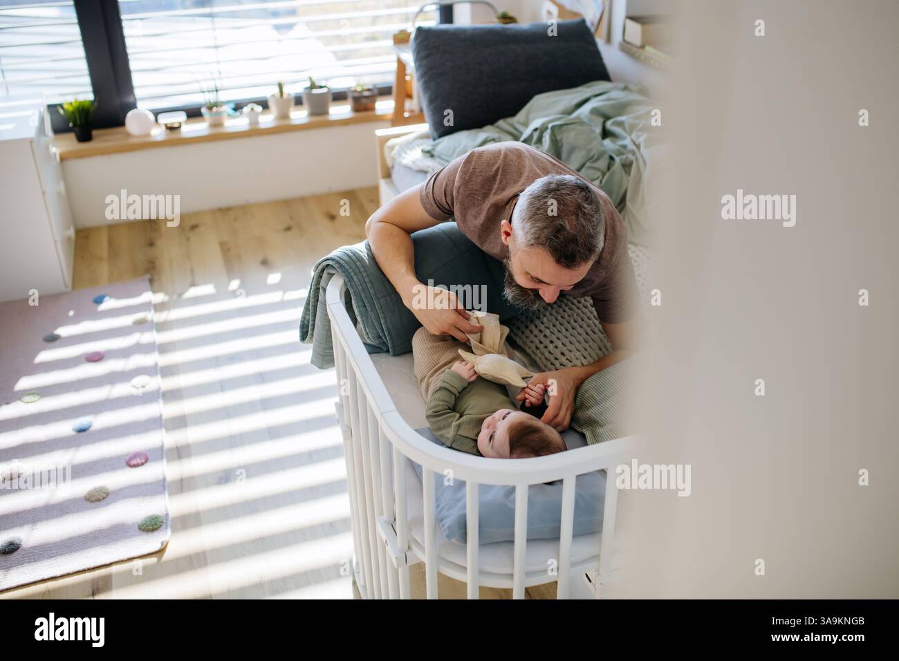 Father putting the baby to sleep, lying next to him in the crib Stock ...