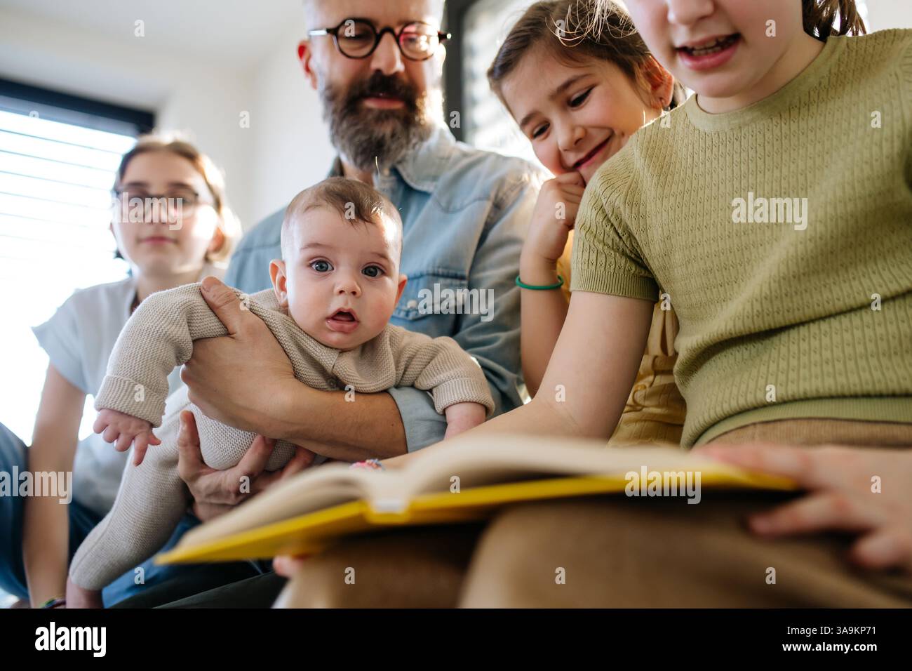 Three sisters and father taking care of newborn brother Stock Photo - Alamy