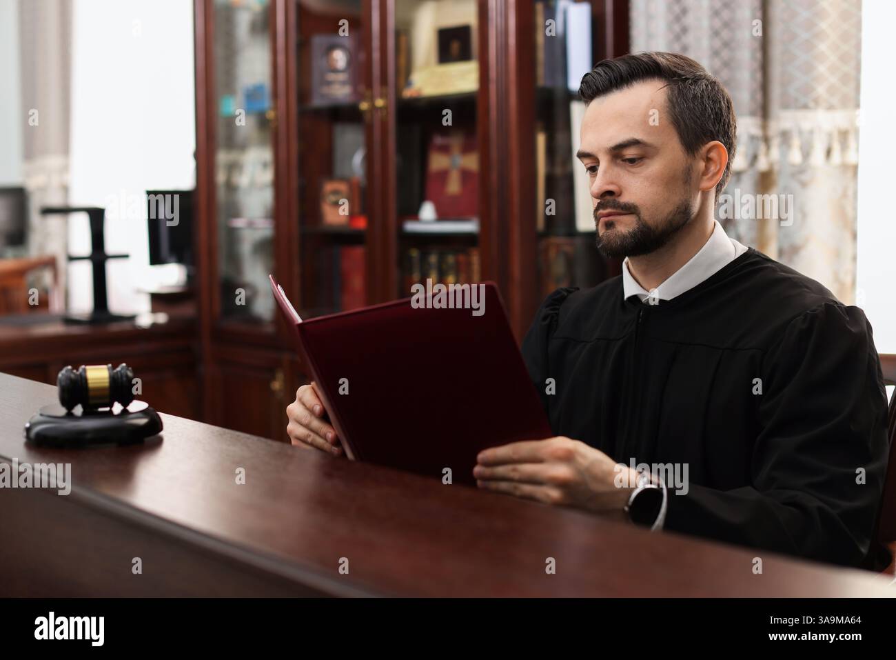 Judge with folder of documents at wooden table in courtroom Stock Photo ...