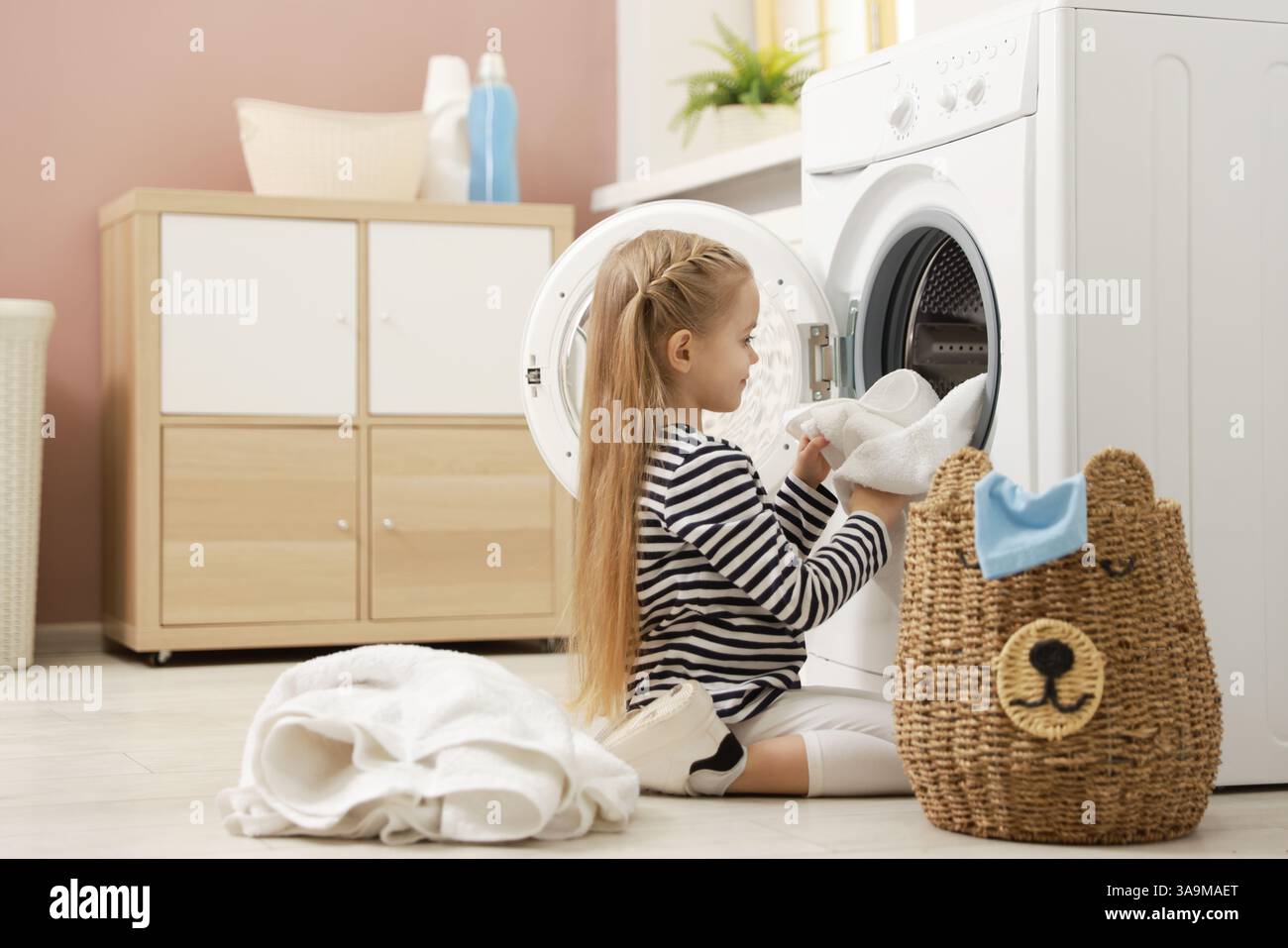 Cute little girl doing laundry at home Stock Photo - Alamy