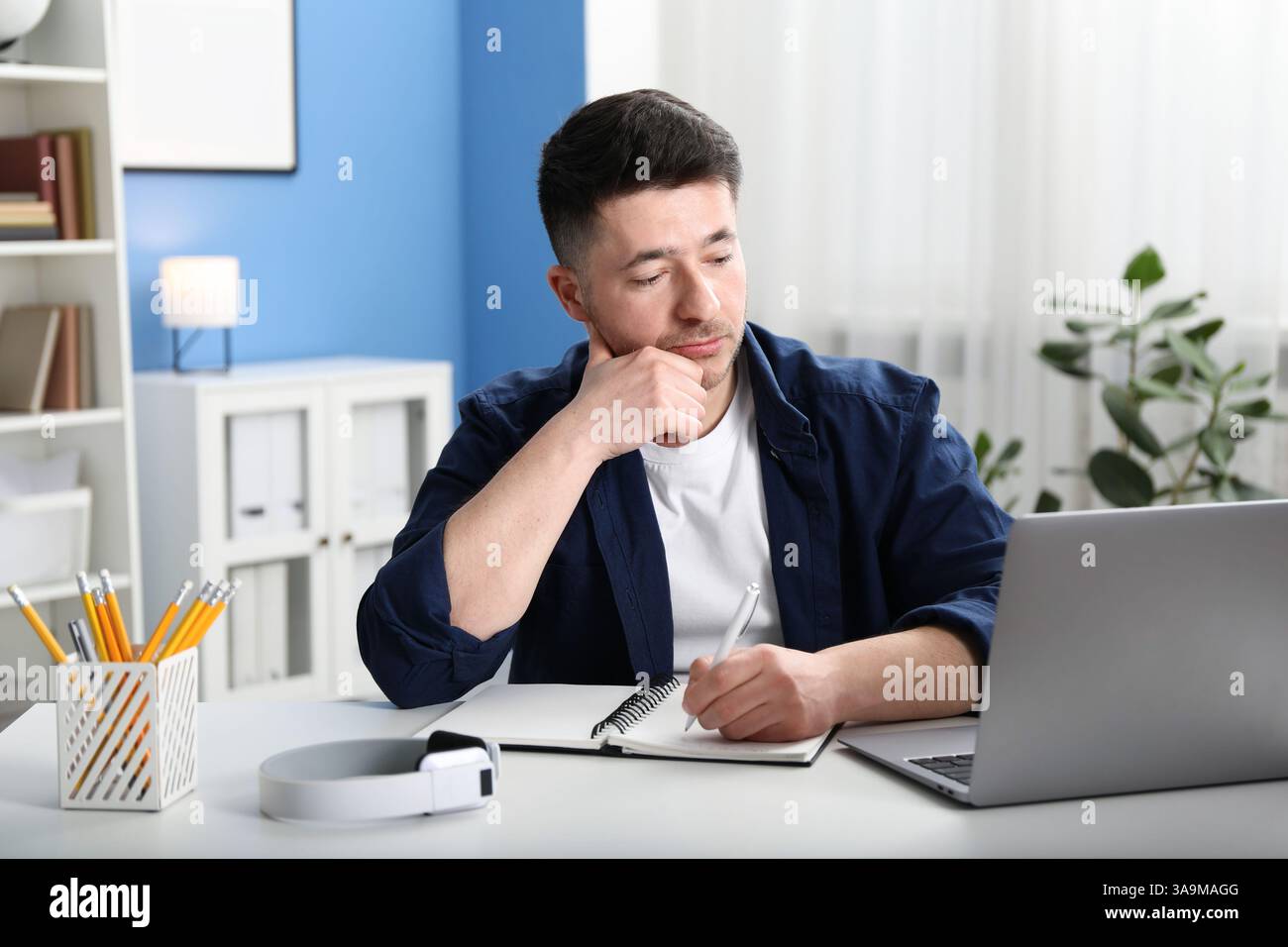 Man taking notes during online lesson at desk indoors. Self-study Stock ...