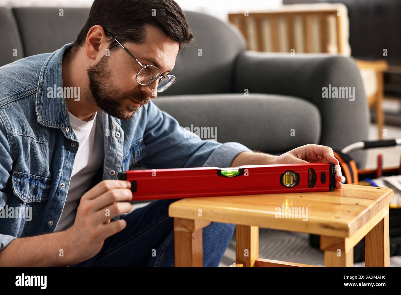 Man using level tool while repairing wooden stool at home Stock Photo ...