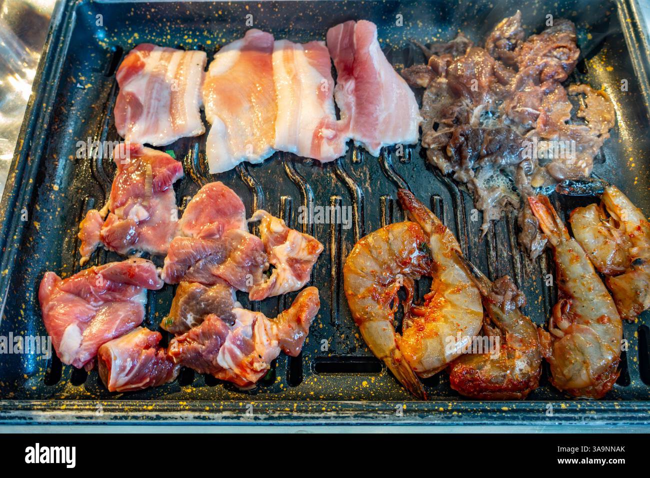 Meat cooking on a Korean Barbeque in a Korean restaurant. The meal is ...