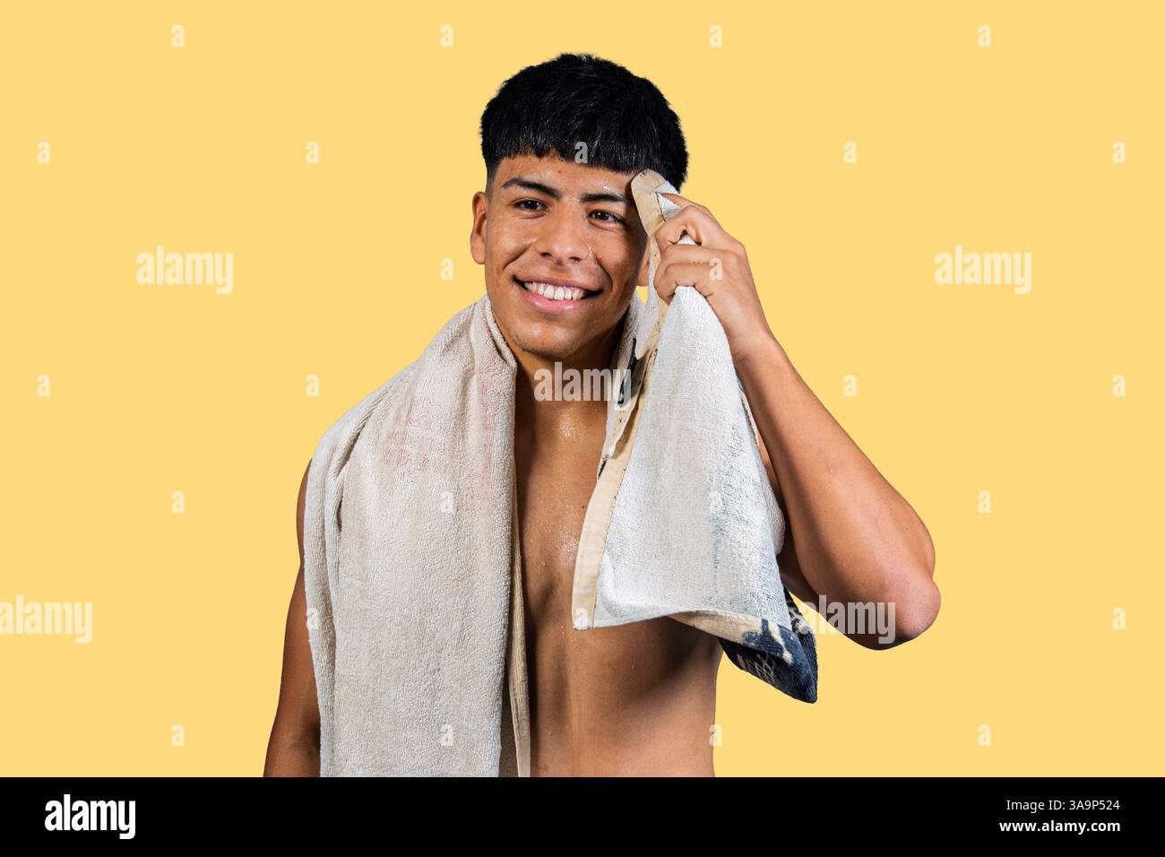 Smiling sportsman drying his forehead with a towel after training ...