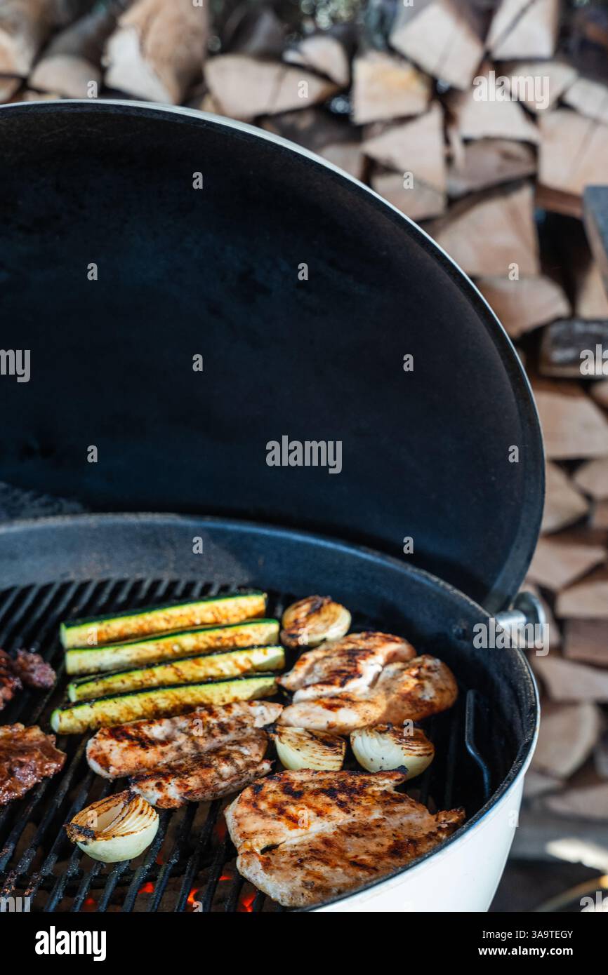 Backyard Grill with Chicken and Veggies by Firewood Stack Stock Photo ...