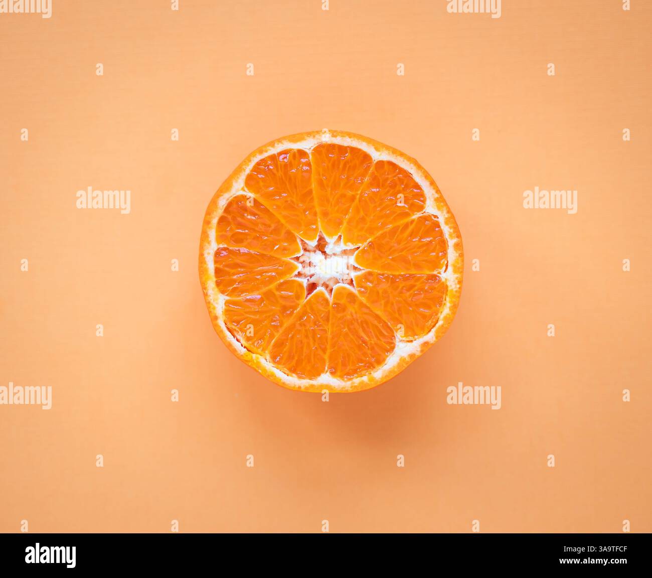 Overhead view of clementine cut in half on orange background Stock ...