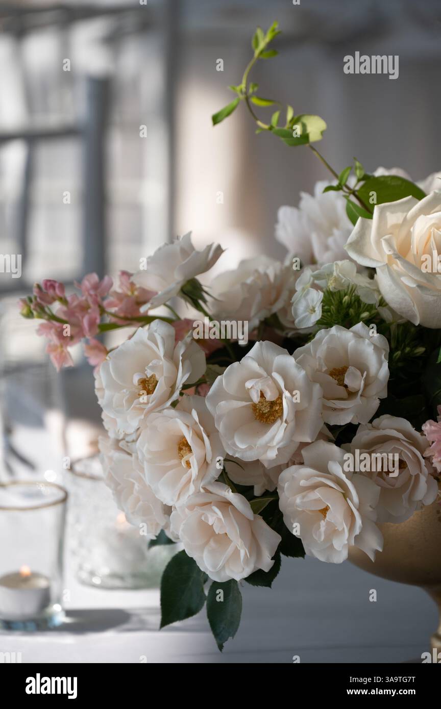 Creamy white roses and blush blooms in a soft-lit floral centerp Stock ...