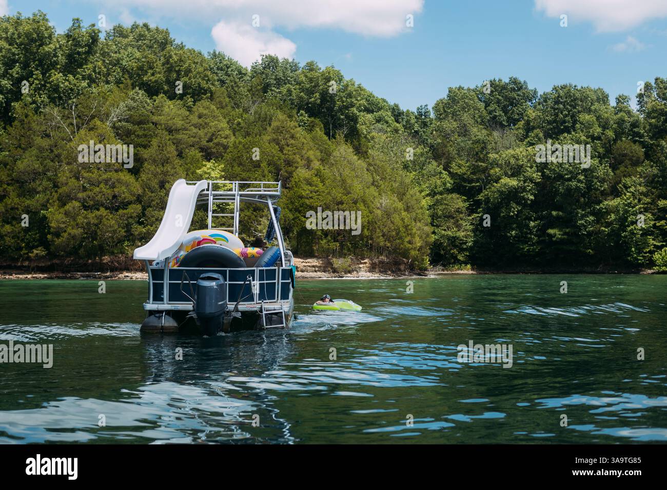 Woman floating next to pontoon boat in lake on summer day Stock Photo ...
