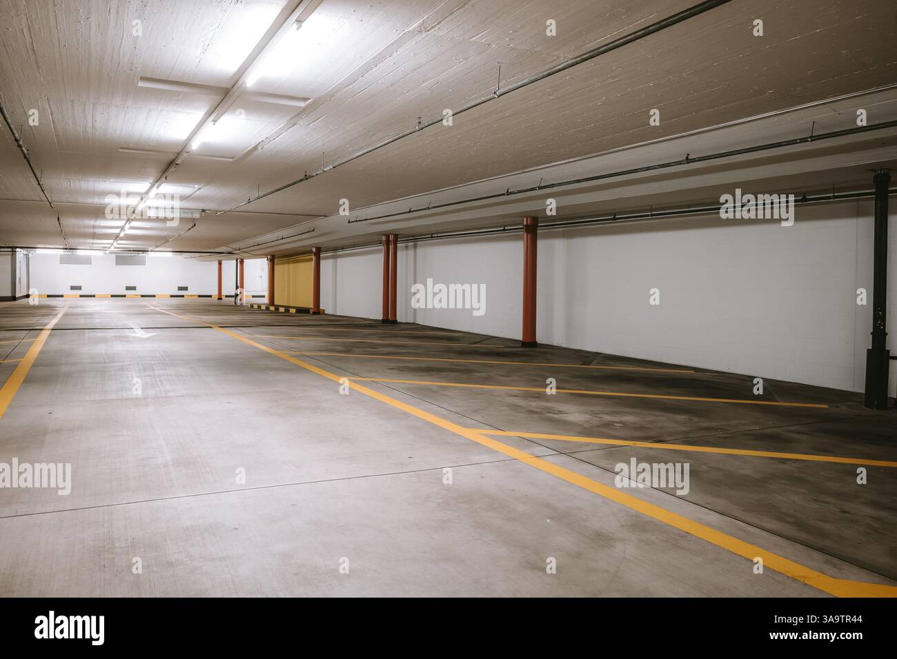 Empty, illuminated underground car parking lot. Wide angle view, no ...