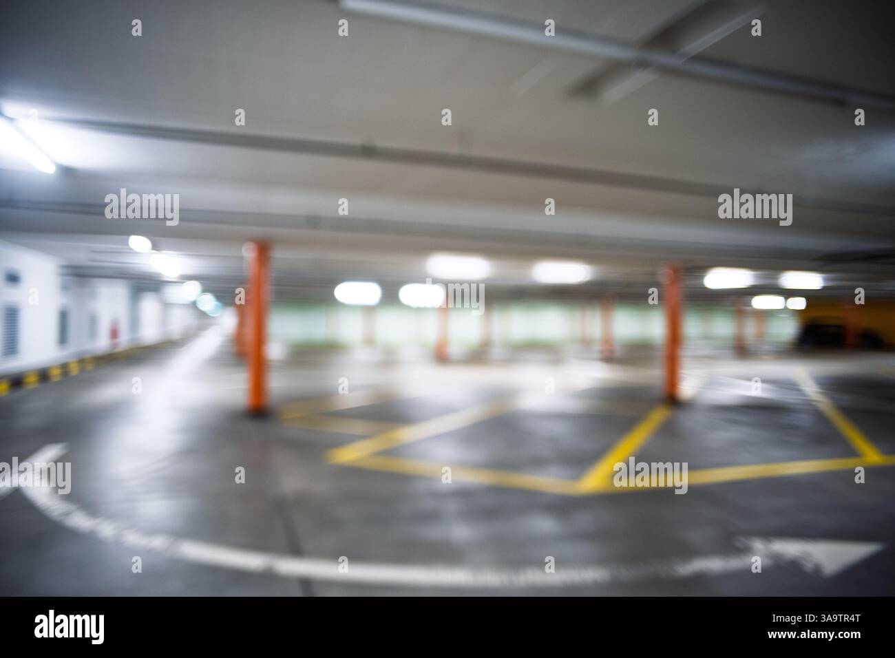 Blurred, empty, illuminated underground car parking lot. Wide angle ...