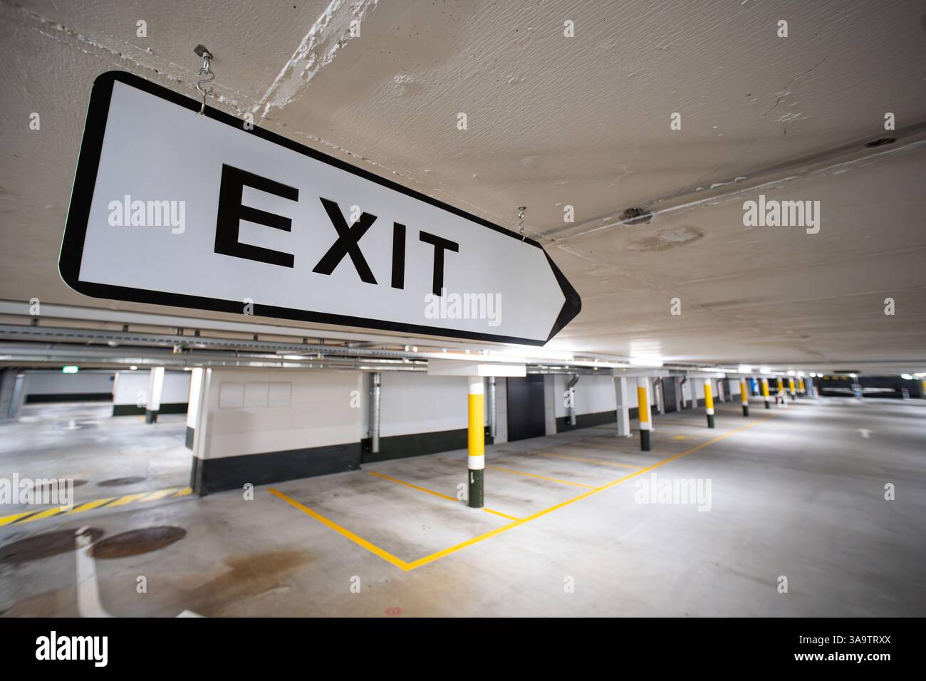 White, large, pointed or directional exit sign inside empty public ...