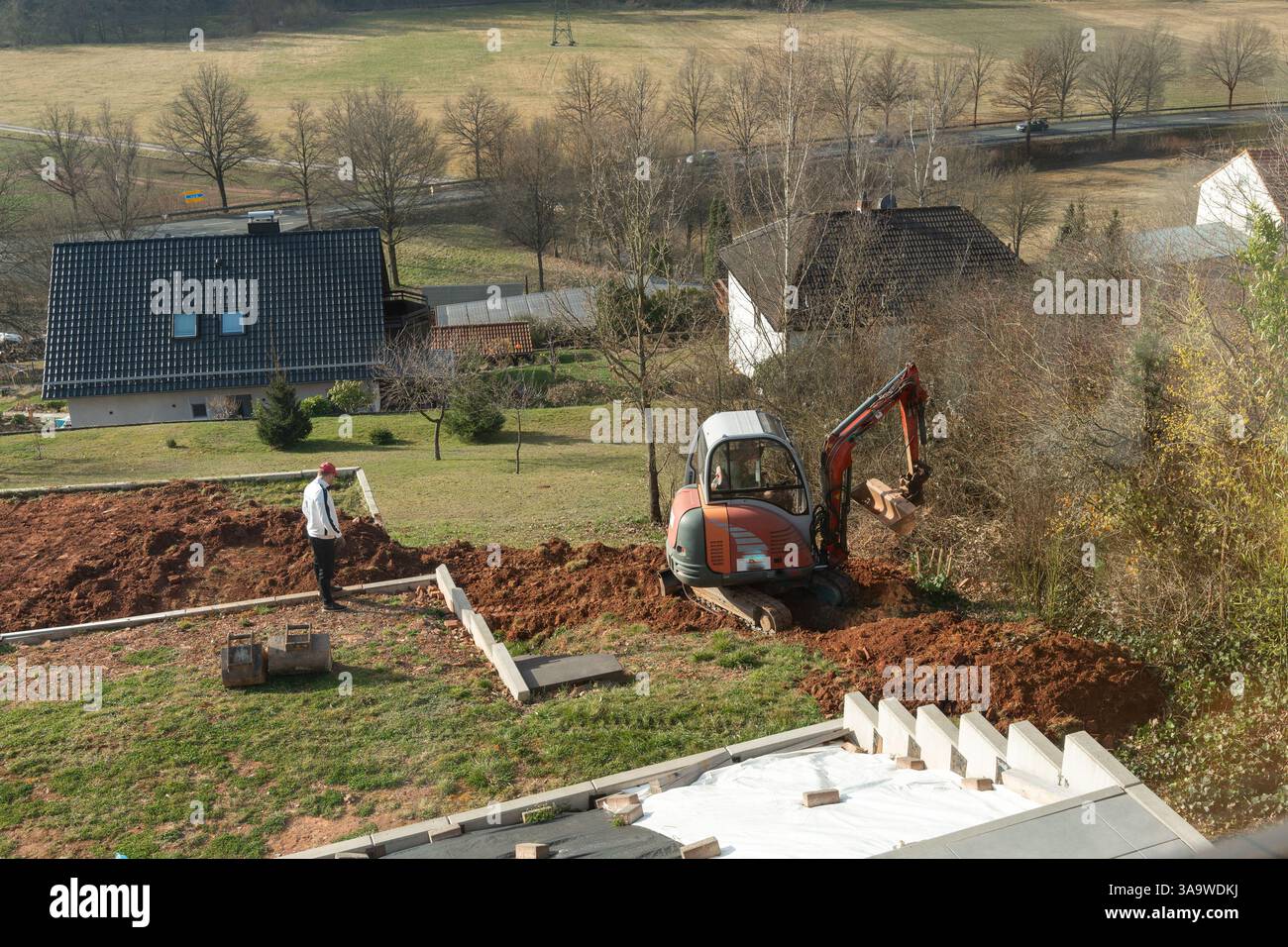 Excavator actively digging in a residential construction site with a ...